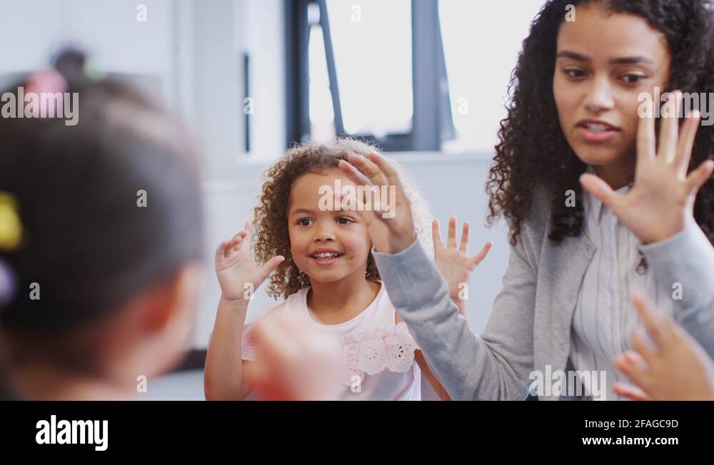 A class of infant school children using their hands to count with their ...