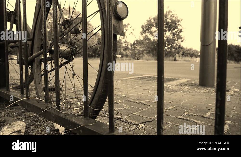 Close view of the wheel of a bike tied to a gate with cars behind Stock ...