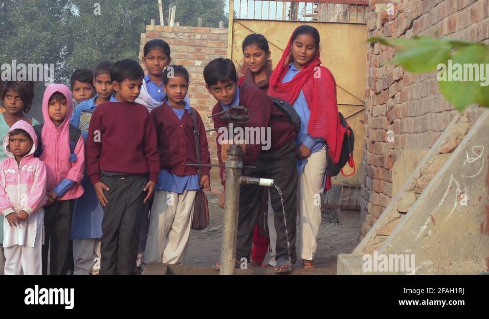 A group of Pakistani rural area school children using a hand pump, In ...