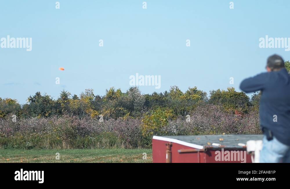 At a shooting range, a man aiming at a flying target with a rifle ...