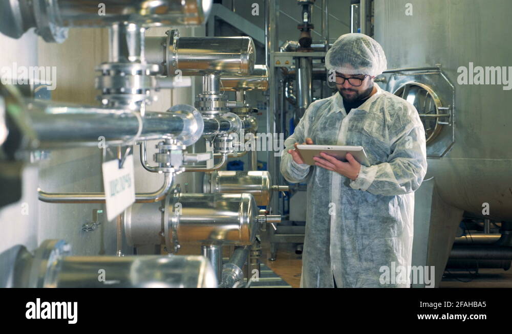 Distillery worker is checking a unit with pipes and reservoirs Stock ...