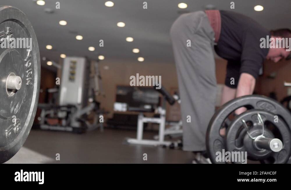 Person exercising and lifting weights in the gym. Slow pan to the right ...