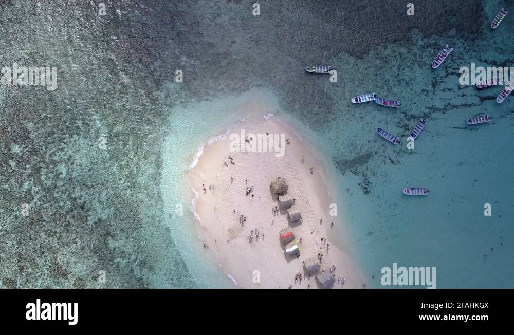 Ascending and rotating aerial view of small sandy island with small ...