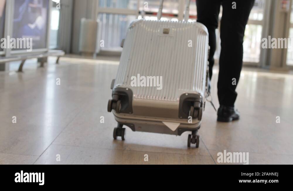 Passenger pulling trolley case through automatic glass door from ...