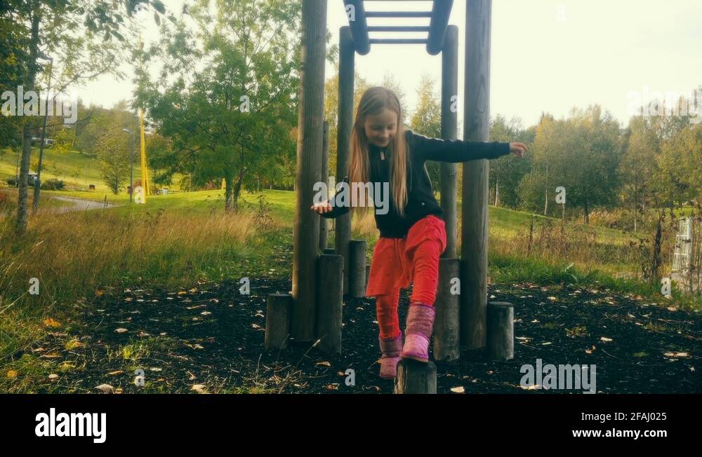 A little girl wearing pink boots is playing happily in a playground as ...