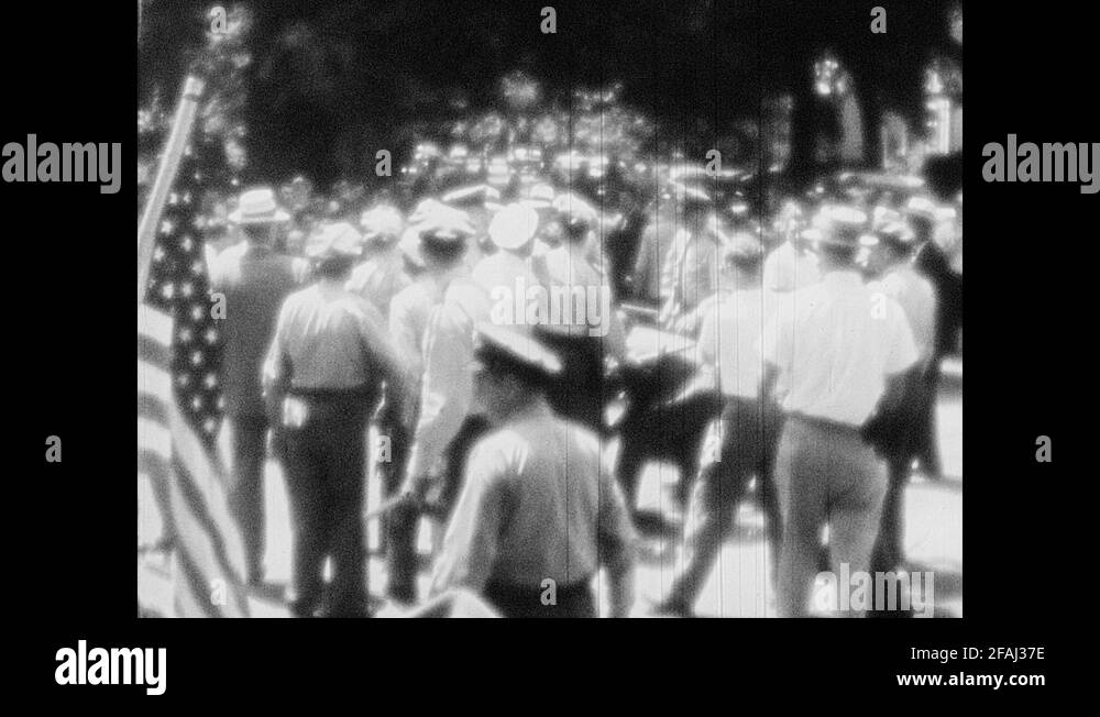 1950s: Unruly crowd. Man yells. Police force suspect into back of ...