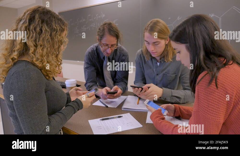 Teacher and three students all using their mobile smart phones in a ...