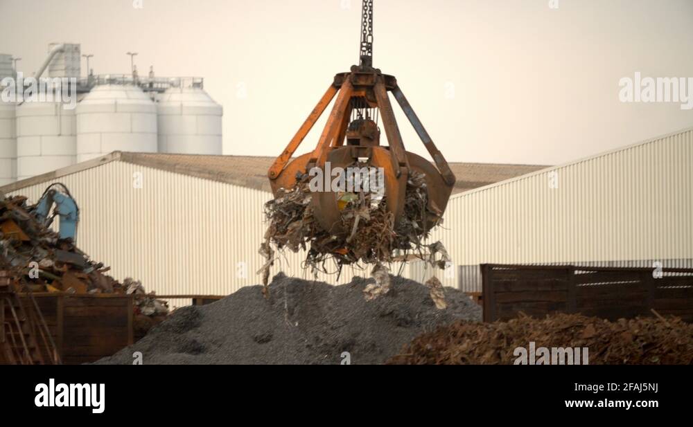 Crane transporting metal scrap into a ship, recycling company in ...