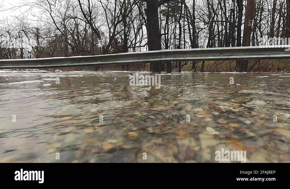Road level footage of floodwaters rising over a bridge inside of a ...