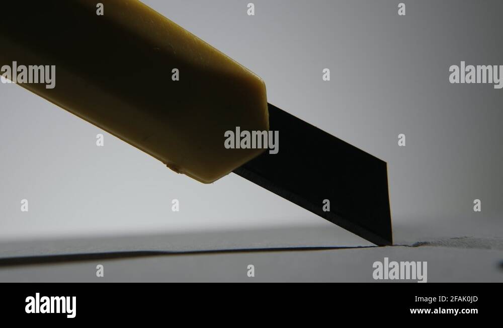 Clerical knife cuts paper, panorama. Close up half silhouette on white ...