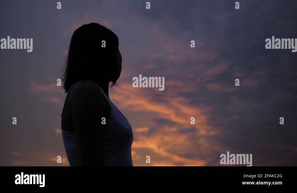 Woman silhouette over sunset sky, dark black shadow of female body with ...