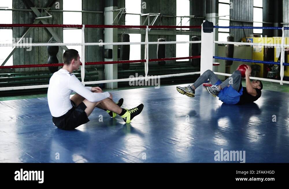 Two muscular men trains in the gym together doing push-ups for abdomen ...