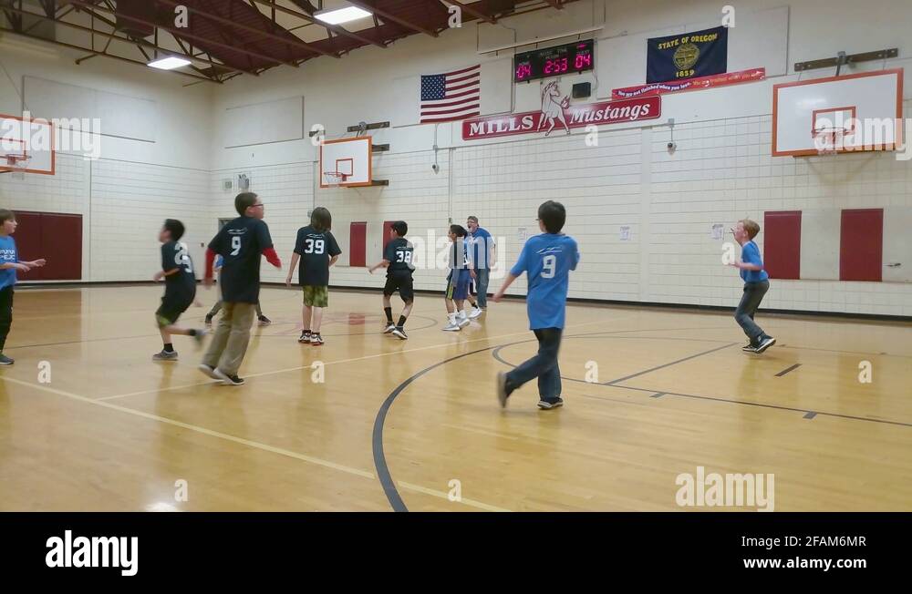 Elementary School kids playing basketball inside a school gymnasium ...