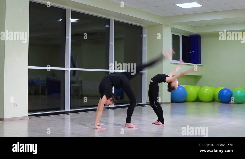 Two girls gymnasts do warm-up and perform exercises in rhythmic ...