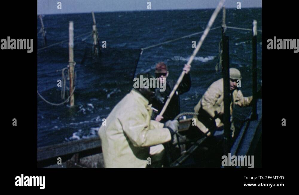 1950s: Men climb from skiff onto boat. Men stand in skiff, check ropes ...