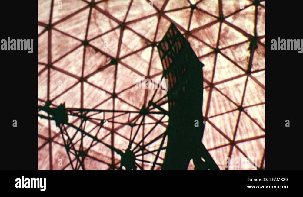 1970s: Radar dish moves around. Men sit at panels in control room ...