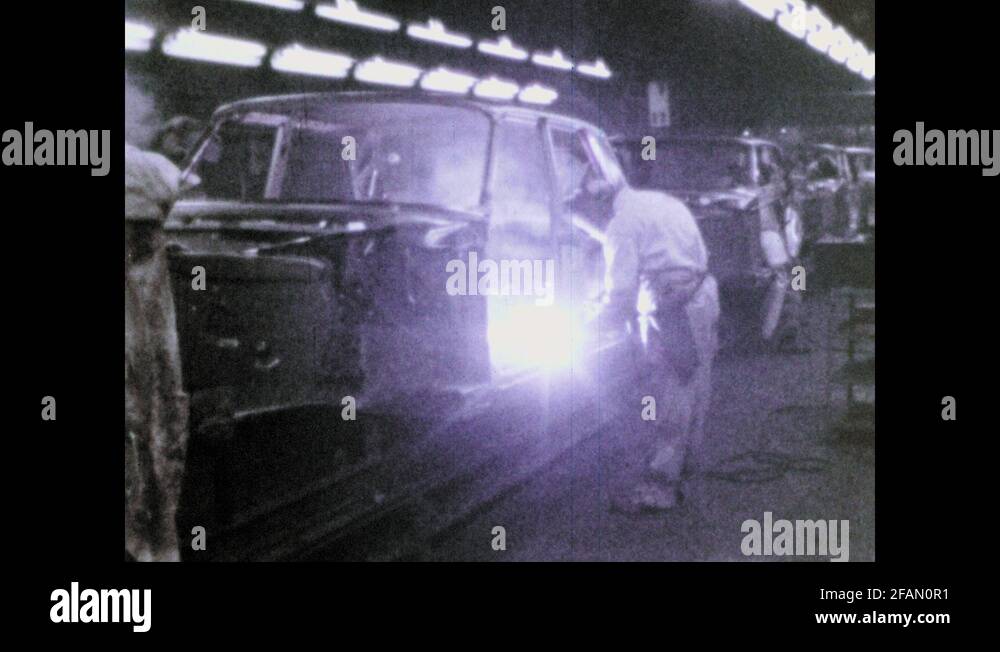 1960s: Workers weld cars on assembly line. Man smoothing side of car ...