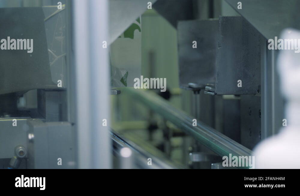 Automated machine cuts lids of plastic containers on a conveyor Stock ...