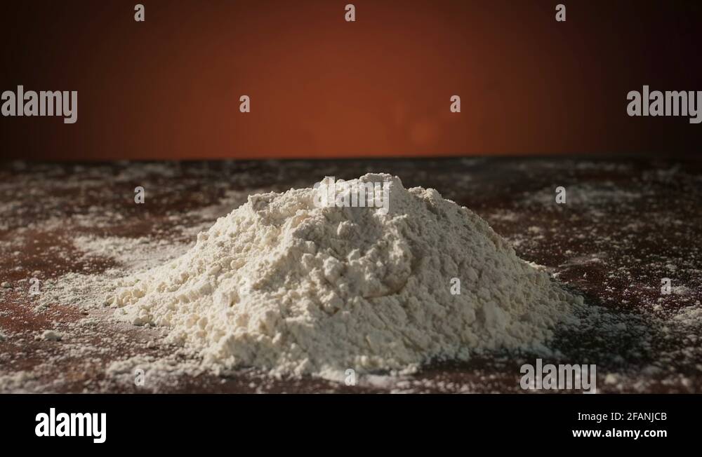 Dough falls on flour creating a splash, slow motion, side view Stock ...