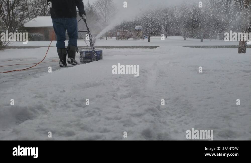 Man push electric corded snowblower to clear snow from driveway Stock ...