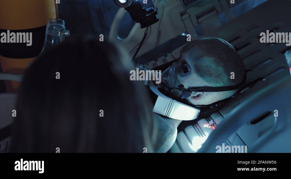 Scientist touches the sensors of the alien. Alien lies on the operating ...