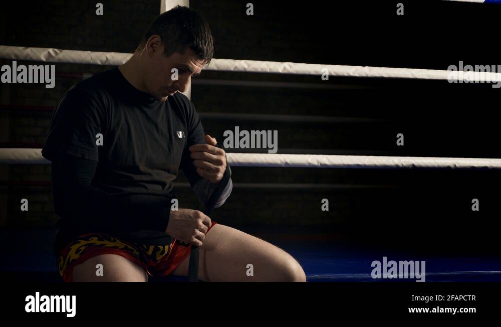 Slow motion Muay Thai Boxer Putting on Hand Wraps While Sitting on ...