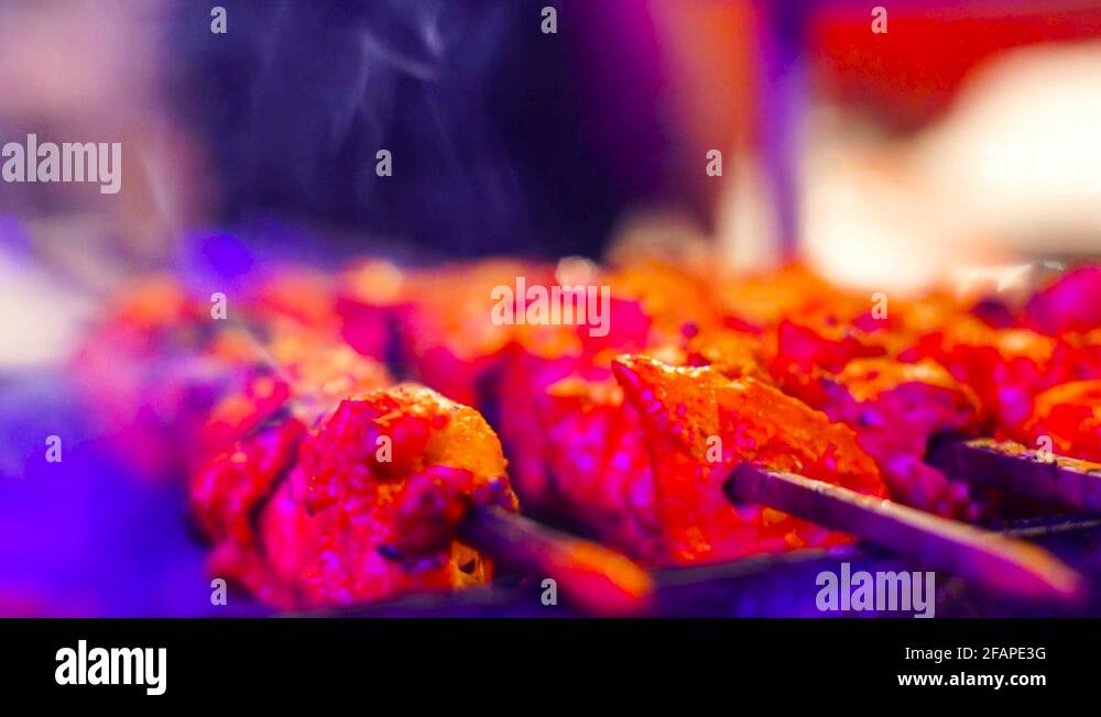 Paneer fish chicken tikka roasting on an open hearth with glowing coals ...