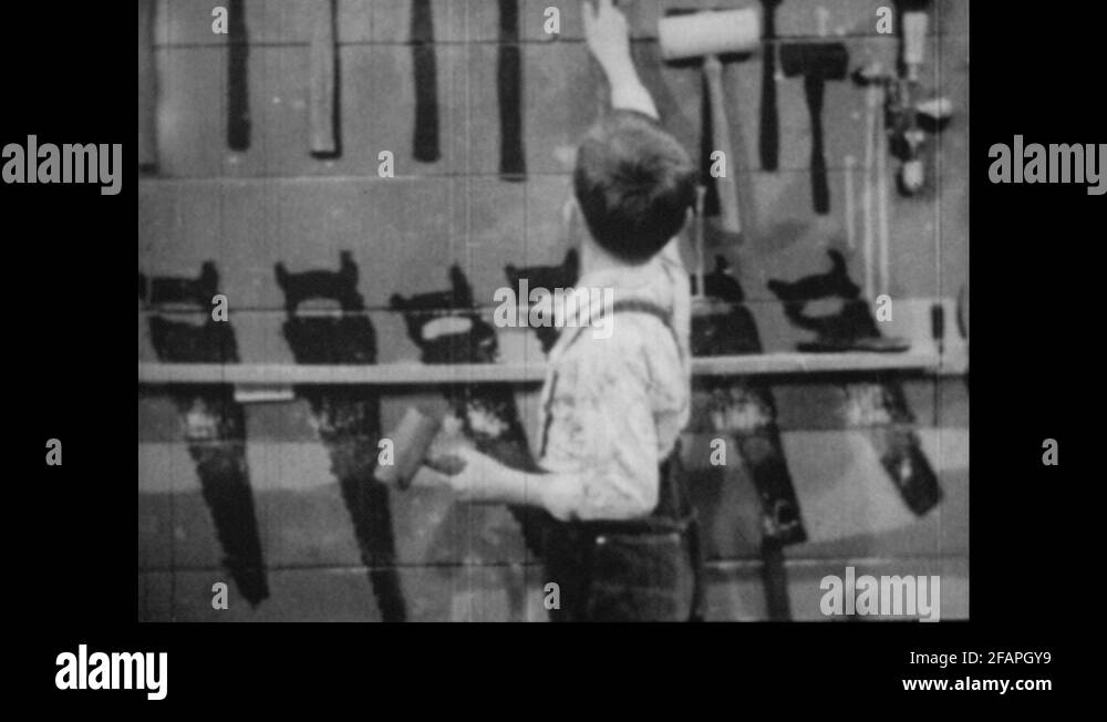 1950s: UNITED STATES: boy organizes tools in classroom. Children play ...