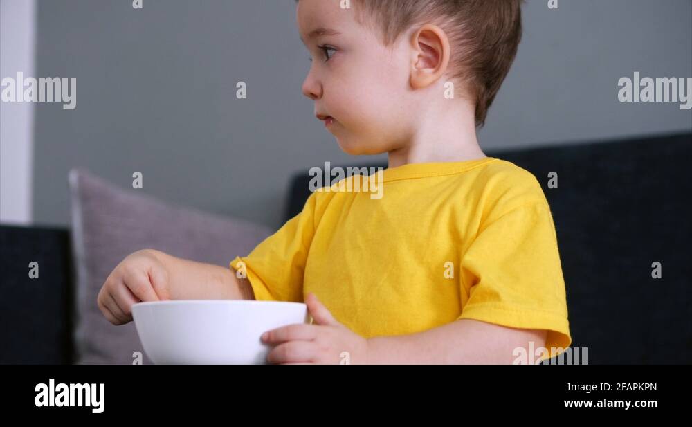 Small Cute Child is Sitting at a Table and eat his own oatmeal, the ...
