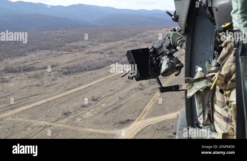 Door gunner firing machine gun from helicopter over Novo Selo Range ...