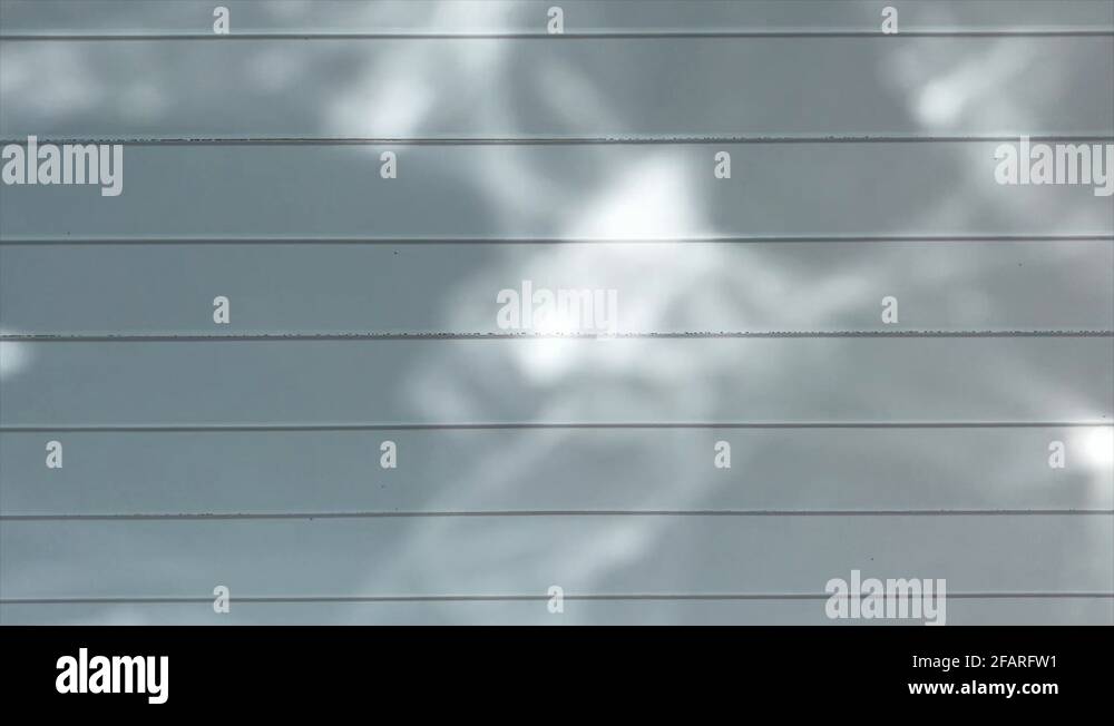Swimming pool ripples reflect on wooden ceiling of pool house on a ...
