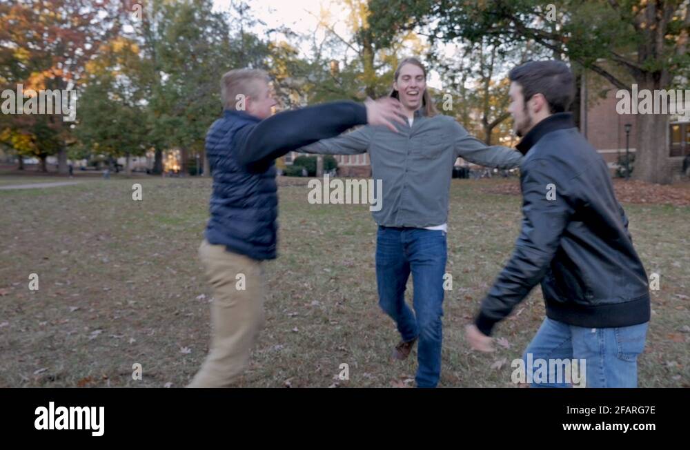 Three college men hug and pat each other on the backs on campus Stock ...