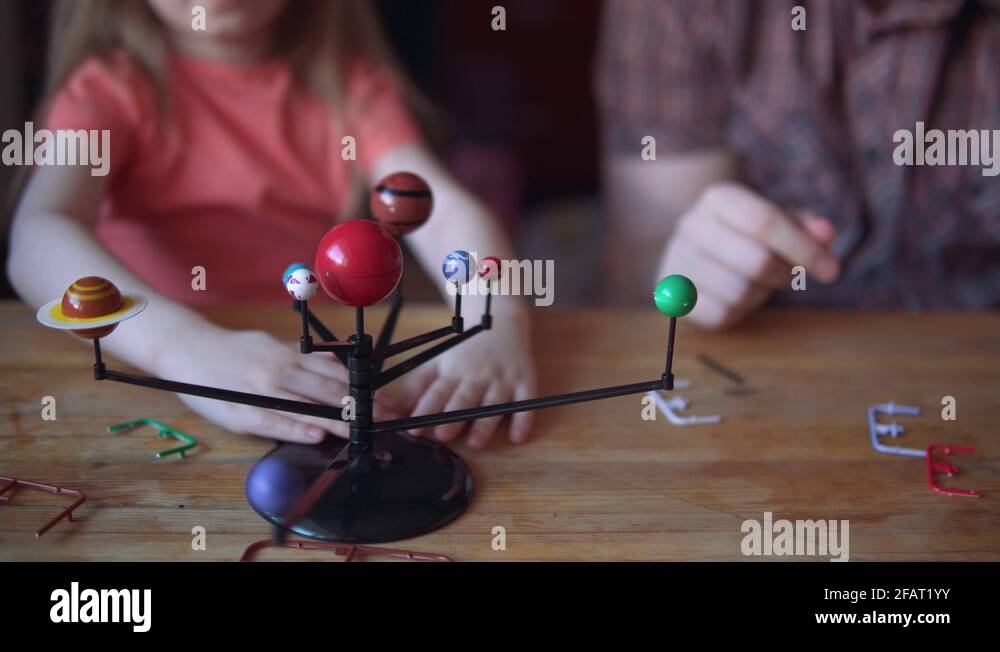Father and cute child make a model of the solar system in the room ...
