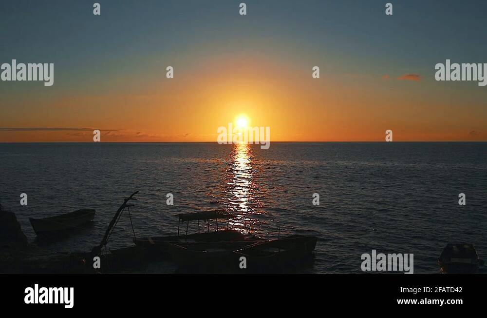 A scenic sunset at Itbayat, Batanes, Philippines with docked boats on ...