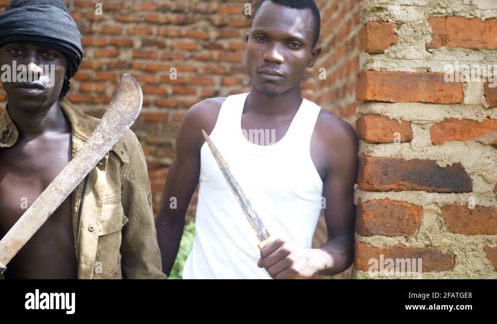 A pan shot of two young African gangsters holding weapons in an ...