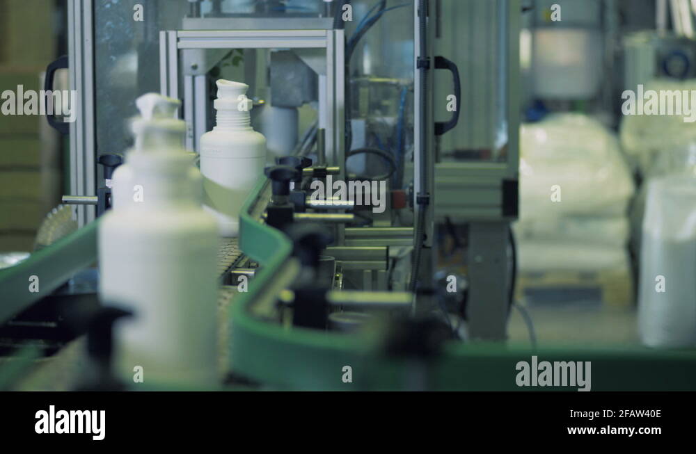 Industrial mechanism is cutting off necks of plastic containers Stock ...