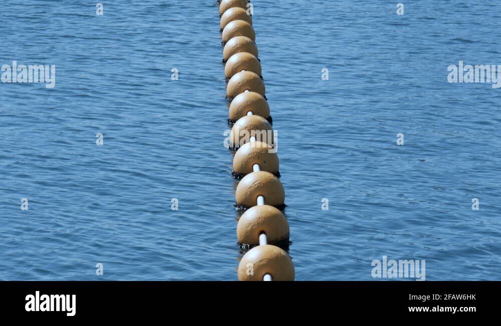 Endless sea view with a chain of yellow coloured buoys. A barrier chain ...