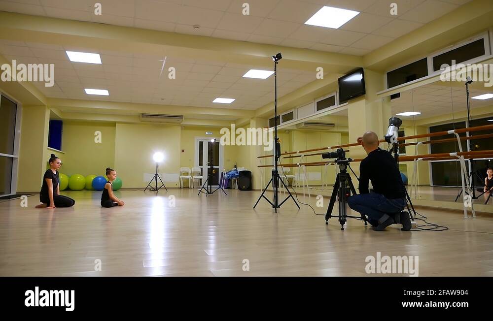 Video cameraman filming as two girls artistic gymnasts make warm-up in ...