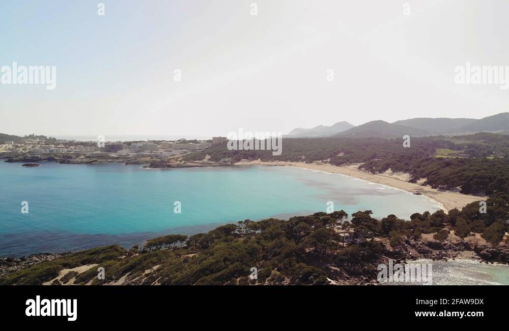 a rotating drone shot that starts at a white sand beach with blue water ...
