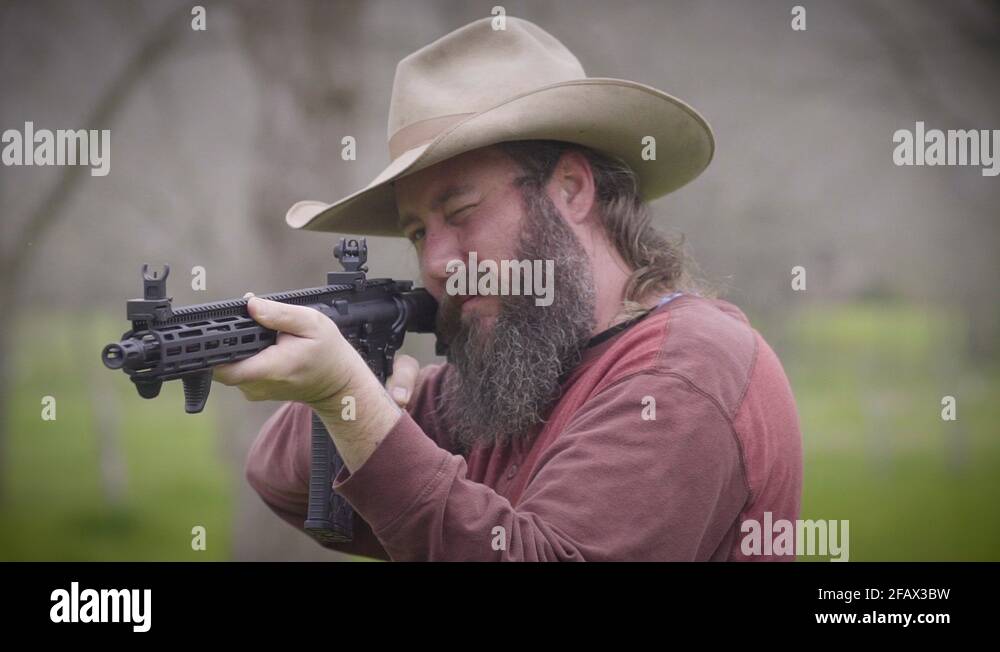 Vintage look, front angle of a cowboy carefully aiming & shooting a ...