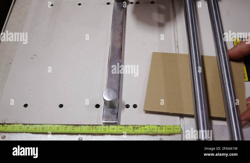 Technician cutting a sample of corrugated cardboard on a guillotine for ...