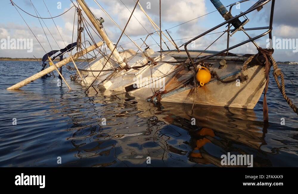 A half capsized yacht sits on its side laying in the water after a ...