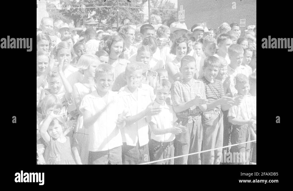 1960s: UNITED STATES: crowd clap at floats. Cowboy in street. Cowboy ...