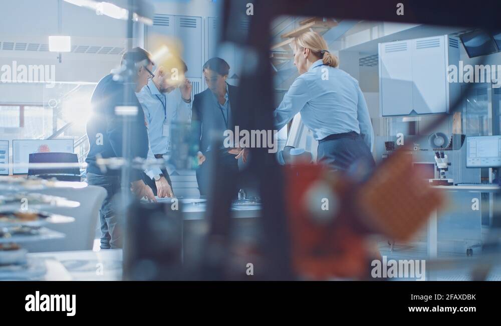 Team of Industrial Robotics Engineers Gathered Around Table With Robot ...