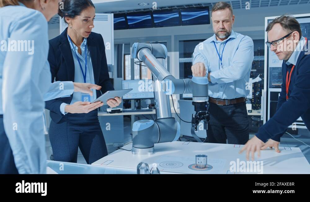 Team of Industrial Robotics Engineers Gathered Around Table With Robot ...