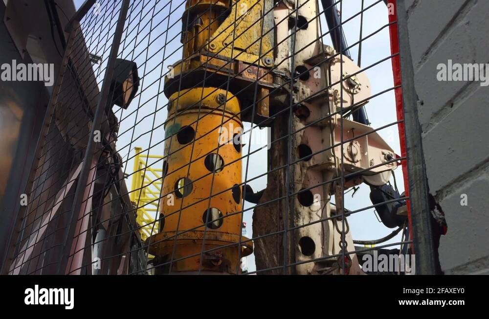 Looking through a fence at a hydraulic rotary drilling rig as it ...