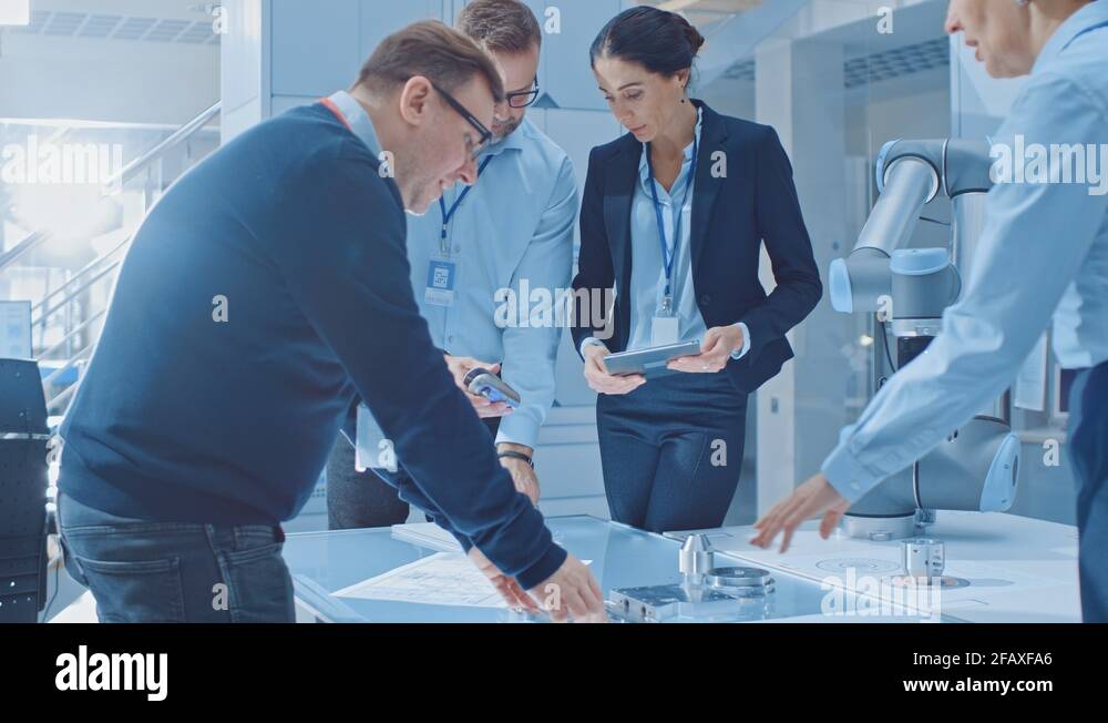 Team of Industrial Robotics Engineers Gathered Around Table With Robot ...