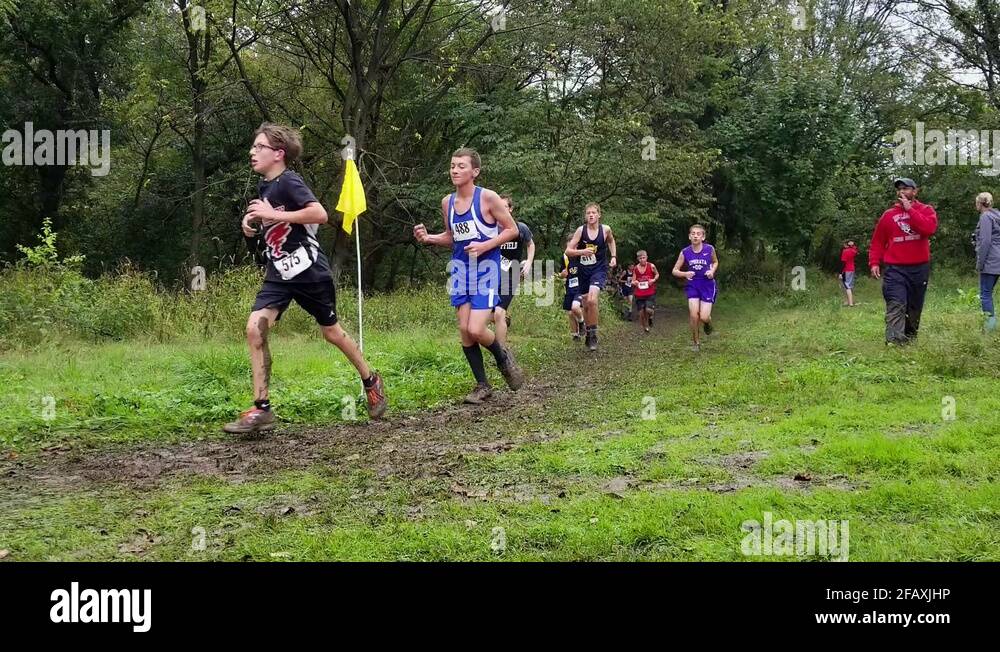 Junior high school children competing in cross country running in mud ...