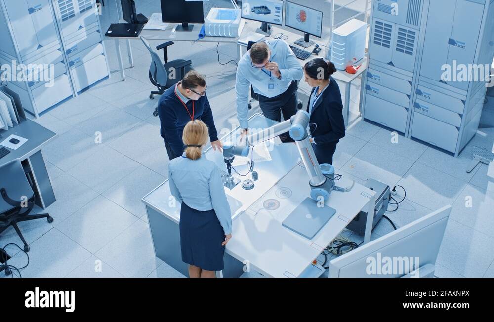 Team of Industrial Robotics Engineers Gathered Around Table With Robot ...