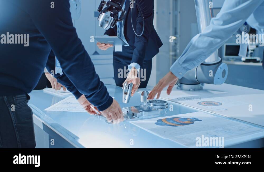 Team of Industrial Robotics Engineers Gathered Around Table With Robot ...